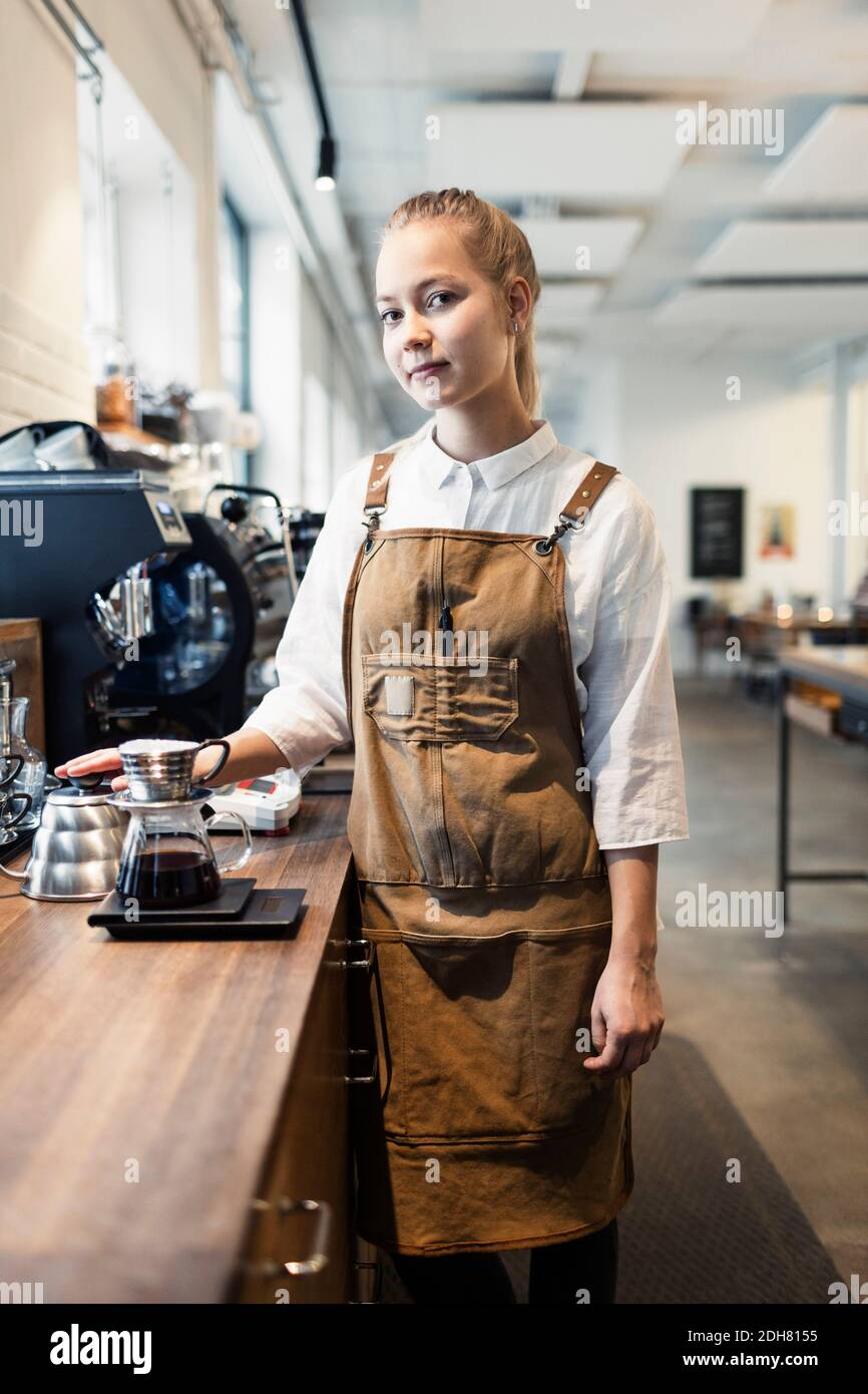 Portrait of confident female barista standing at counter in coffee shop ...