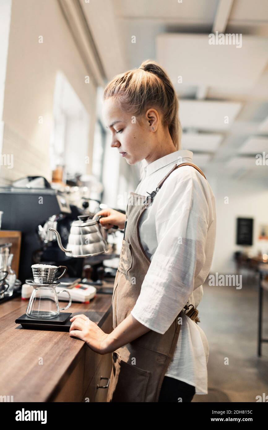 Side view of young female barista making coffee at counter Stock Photo ...