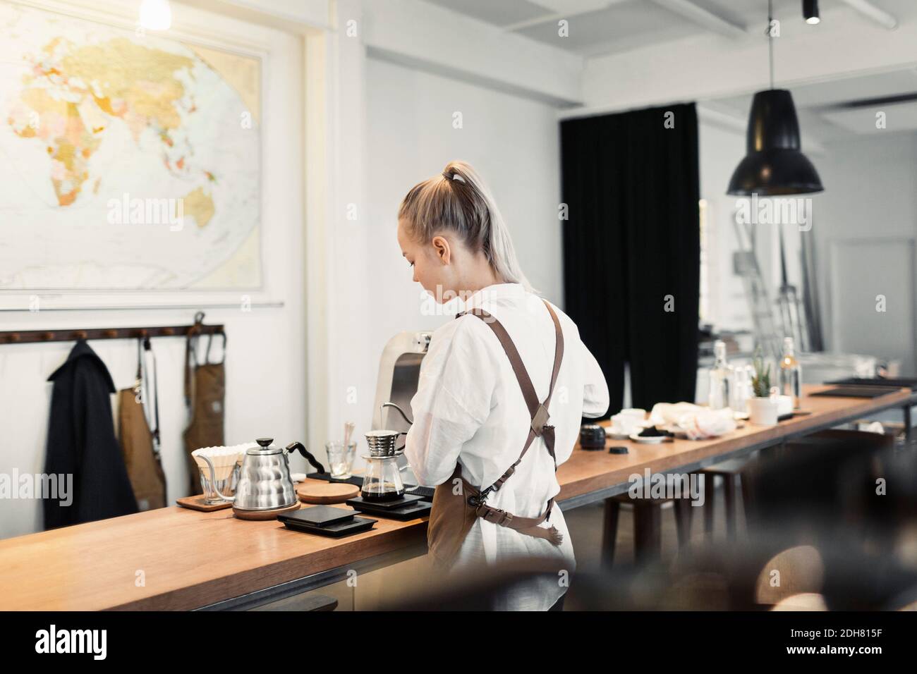 Rear view of young female barista preparing coffee at counter Stock ...