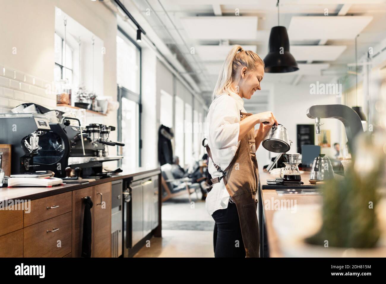 Side view of female barista preparing coffee at counter Stock Photo - Alamy