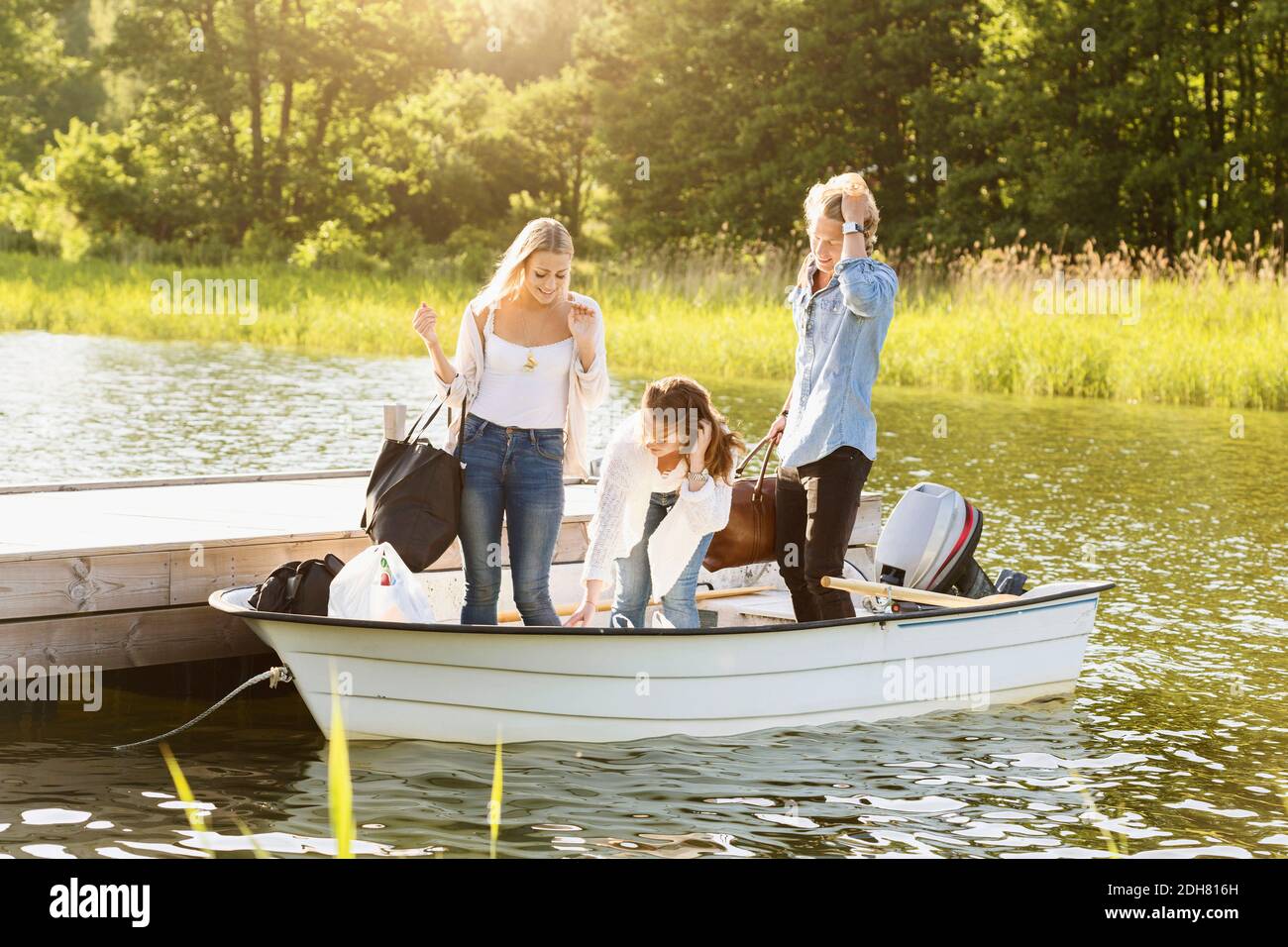 Happy friends with luggage enjoying in boat on lake Stock Photo - Alamy