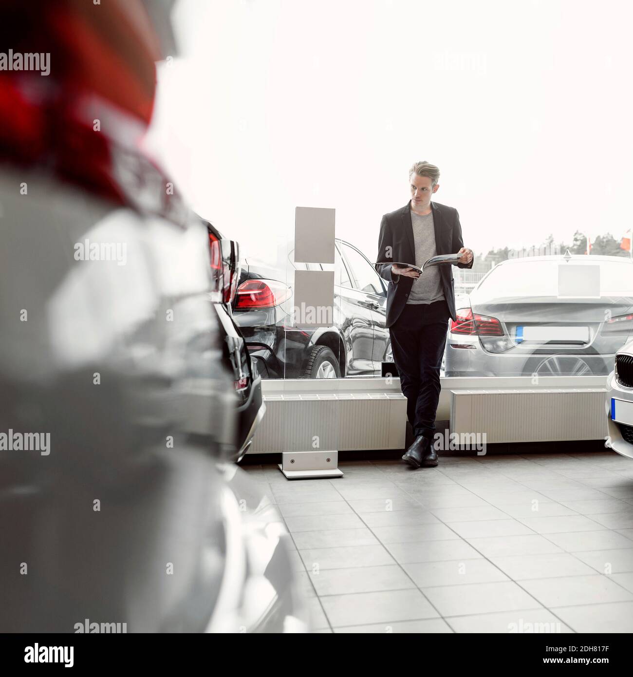 Full length of man reading brochure in car dealership store Stock Photo ...