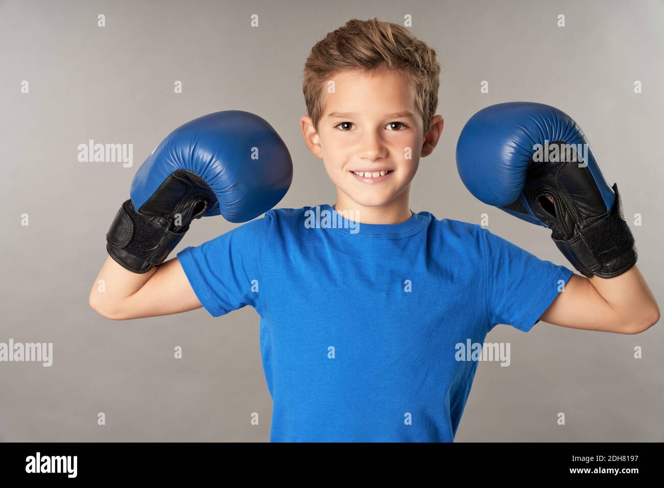 Adorable male kid boxer wearing sports boxing gloves and blue shirt ...