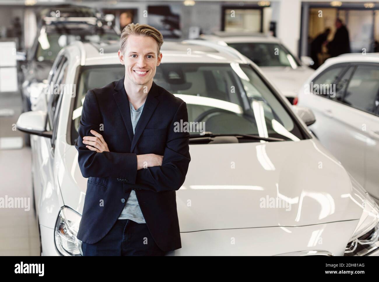 Portrait of happy male customer leaning on car at showroom Stock Photo ...
