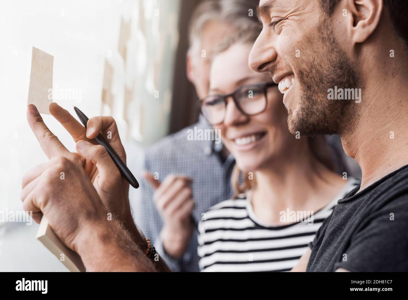 Happy business colleagues writing on adhesive note in office Stock ...