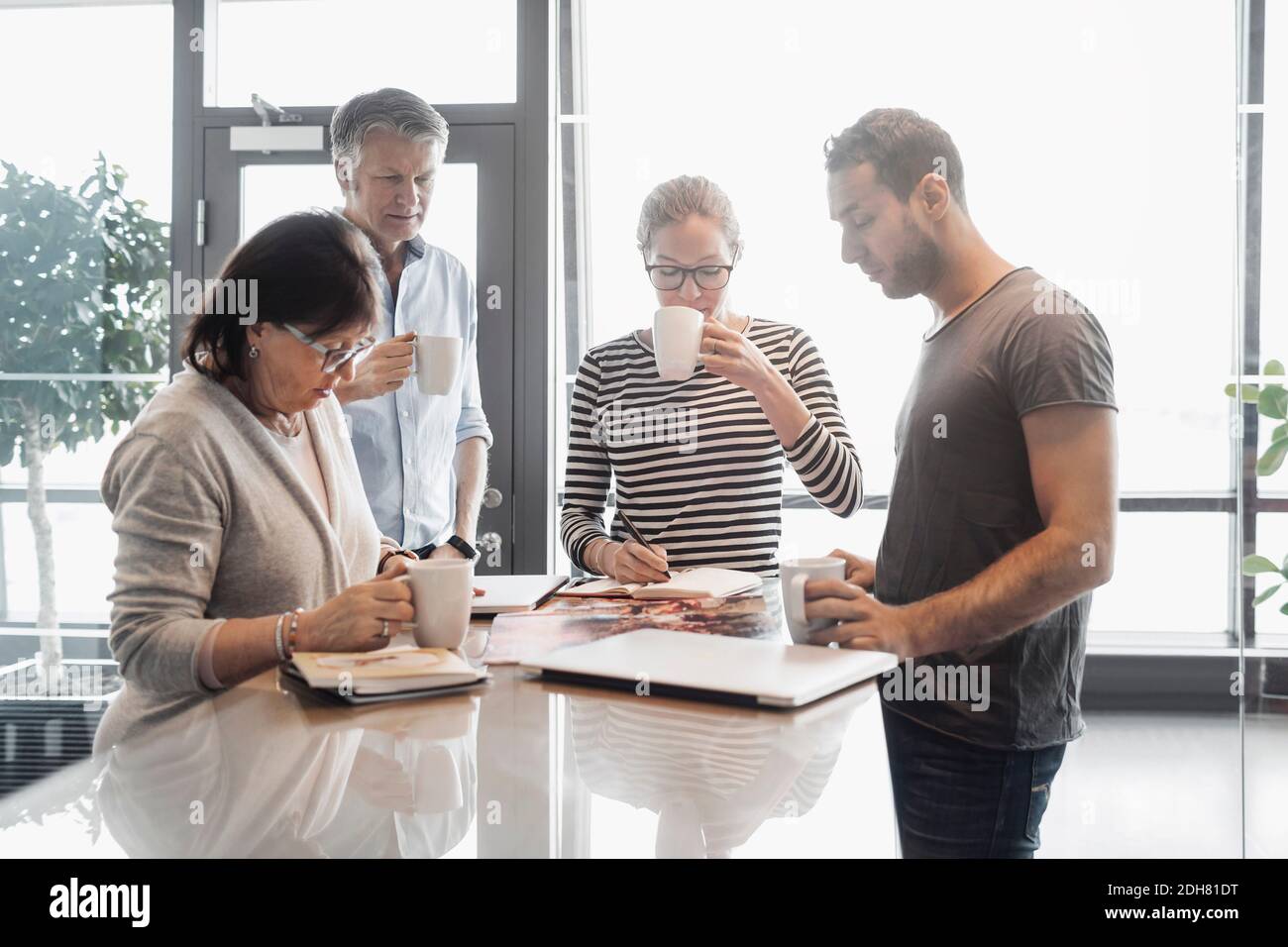 Business people working while having coffee at counter in office cafe ...