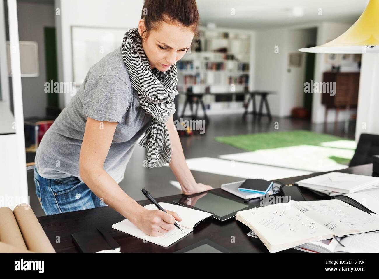 Female architect reading book at table in home office Stock Photo - Alamy