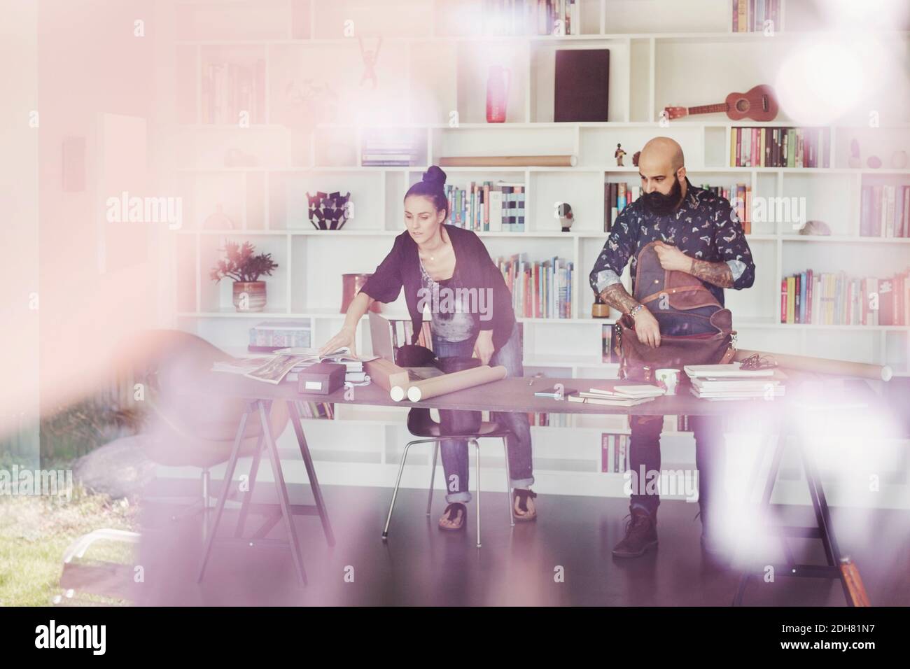 Architects working at table in home office seen through glass window ...