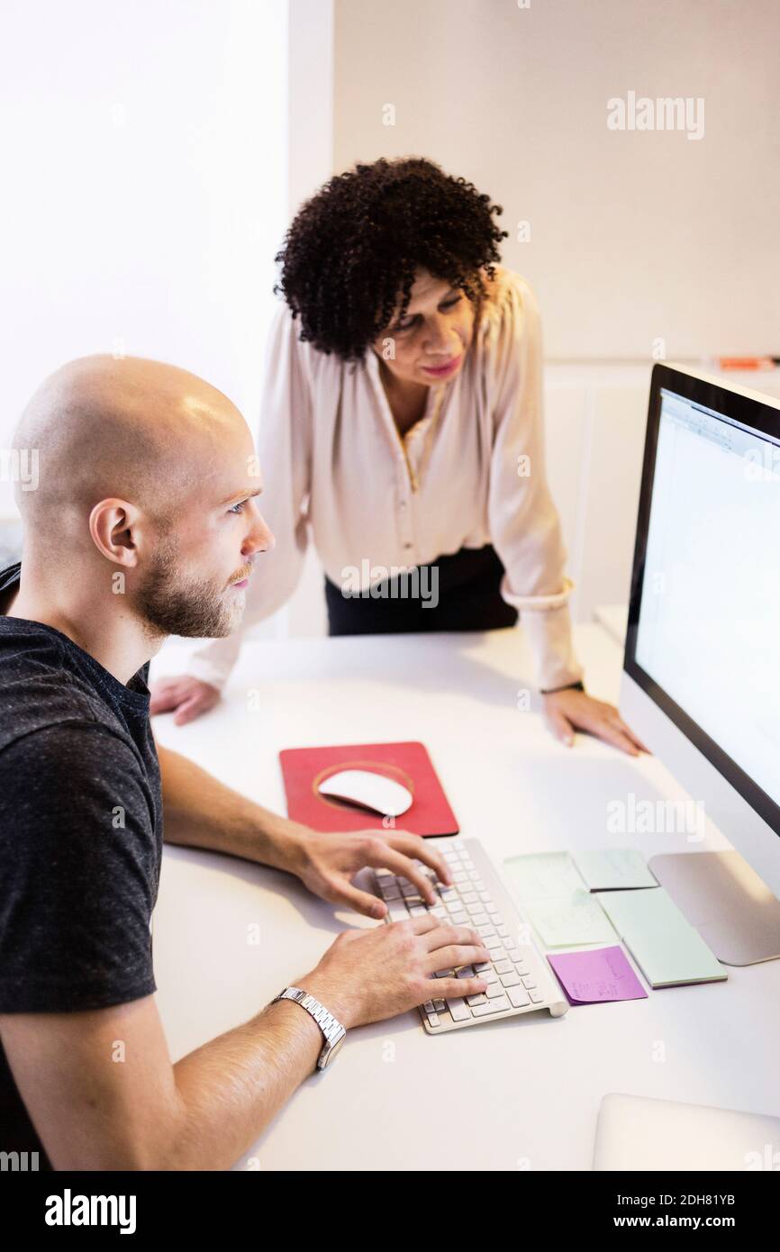 Side view of businessman using computer while colleague looking at it ...