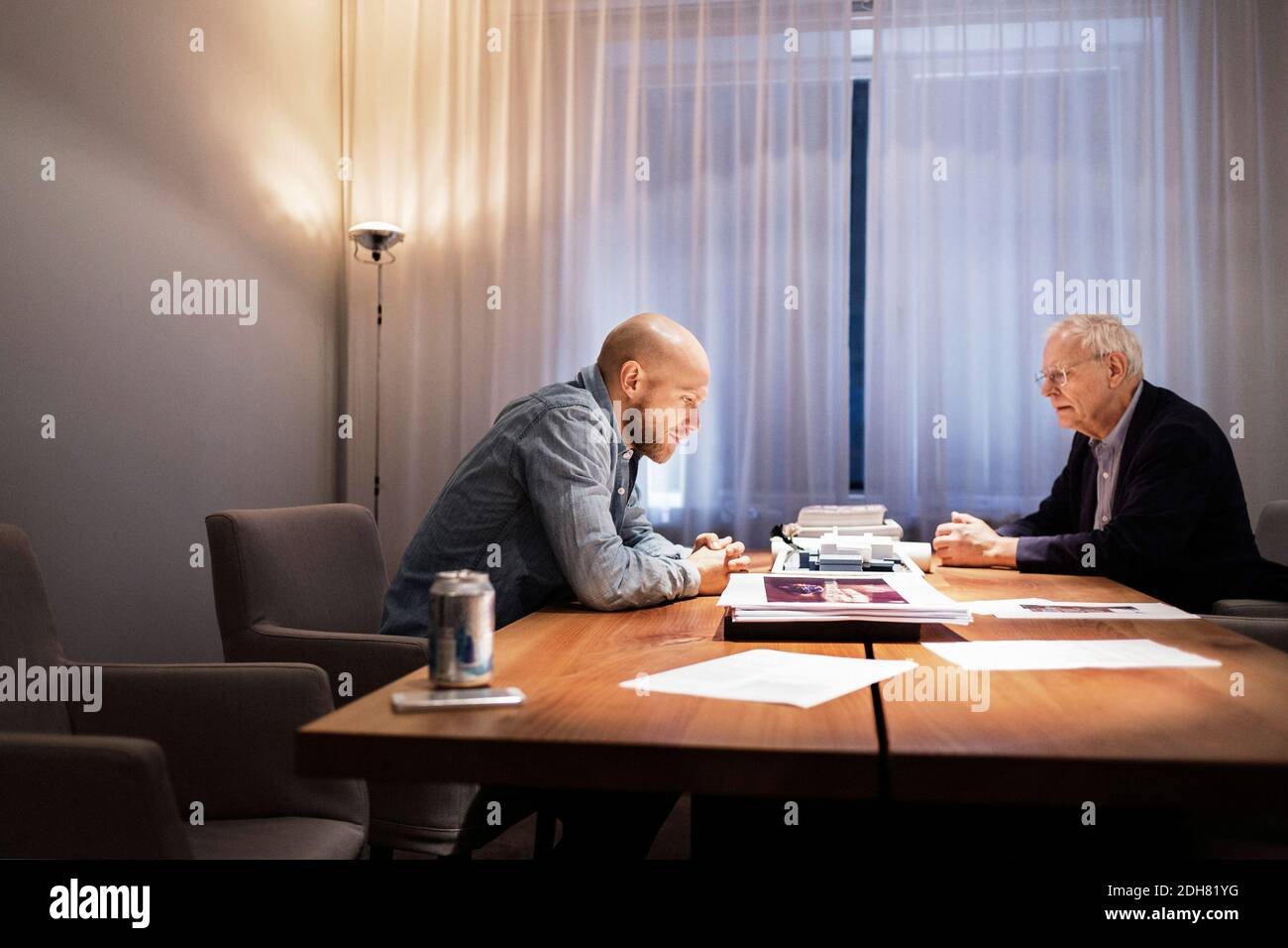 Side view of businessmen sitting at conference table Stock Photo - Alamy