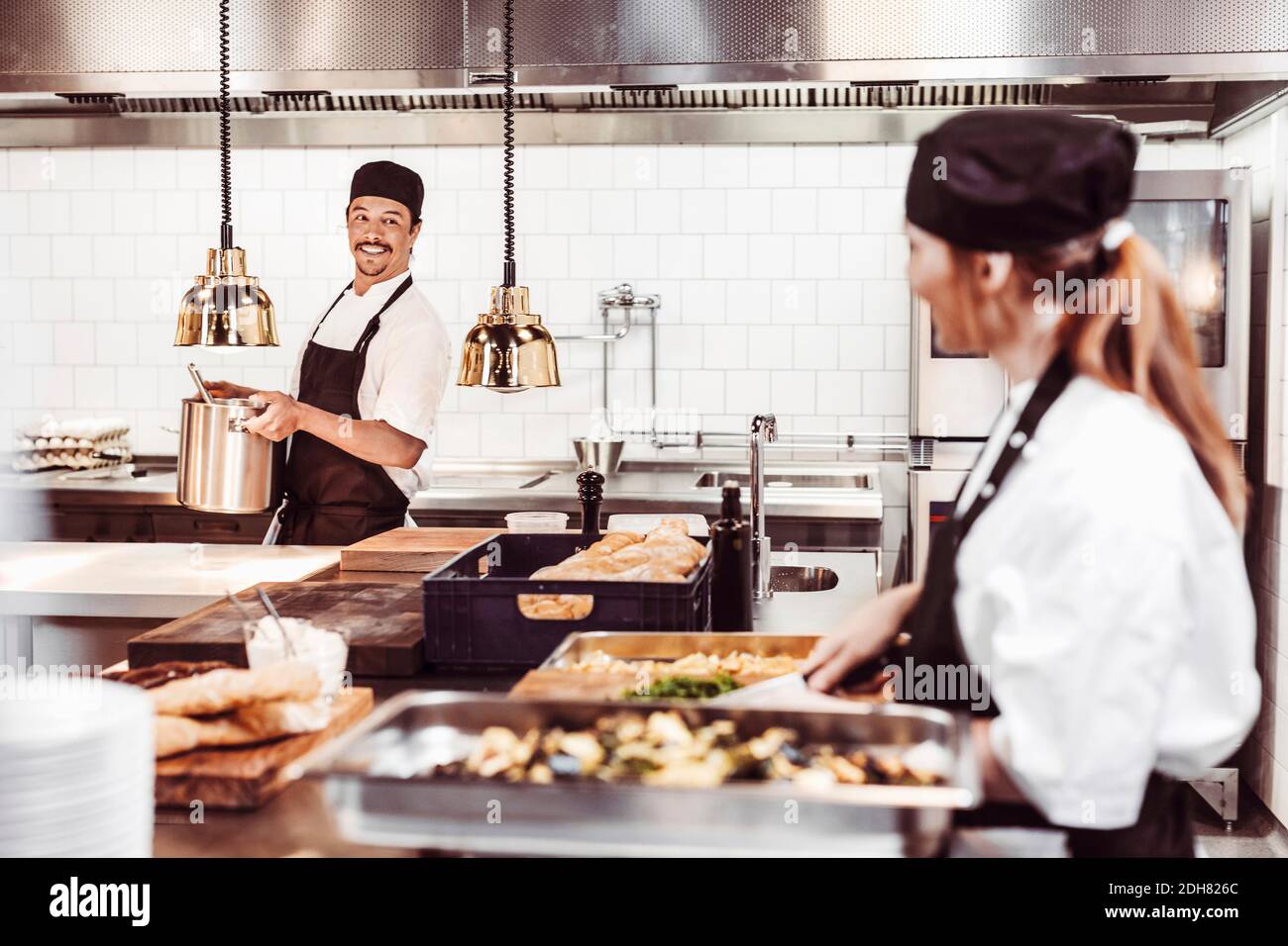 Smiling chefs looking at each other in commercial kitchen Stock Photo ...