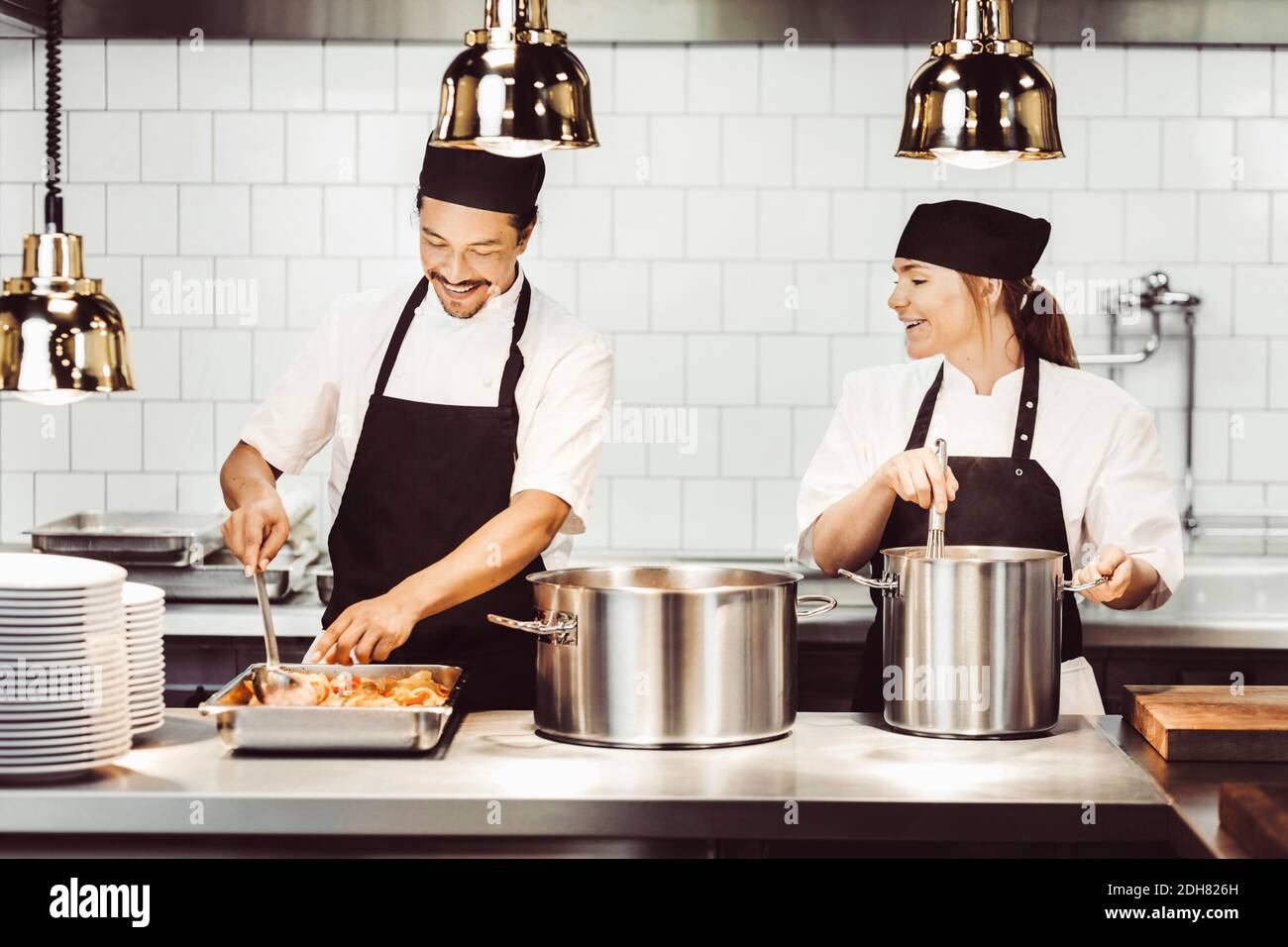 Happy male and female chefs preparing food at kitchen counter Stock ...