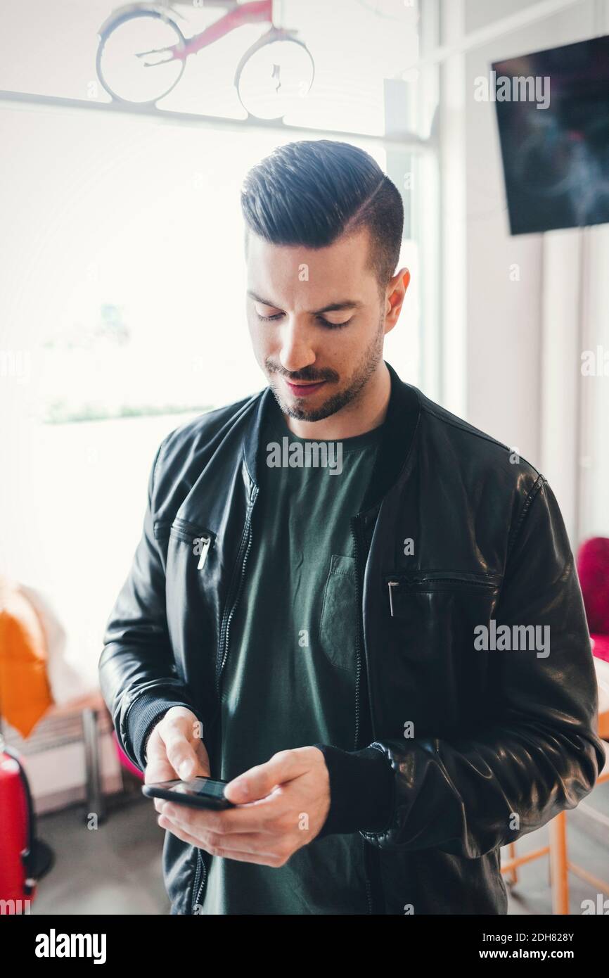 Mid adult customer using mobile phone in repair shop Stock Photo - Alamy