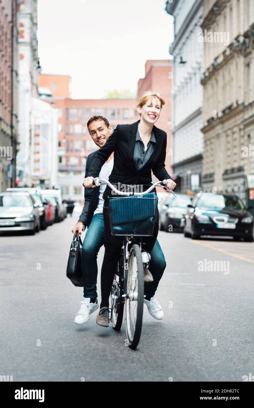 Happy business people riding bicycle on city street Stock Photo - Alamy