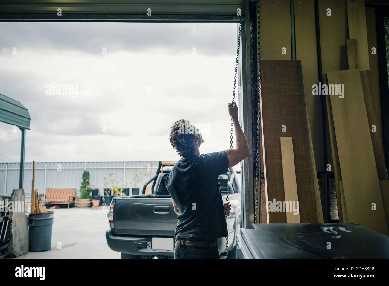 Rear view of carpenter pulling shutter at entrance of workshop Stock ...