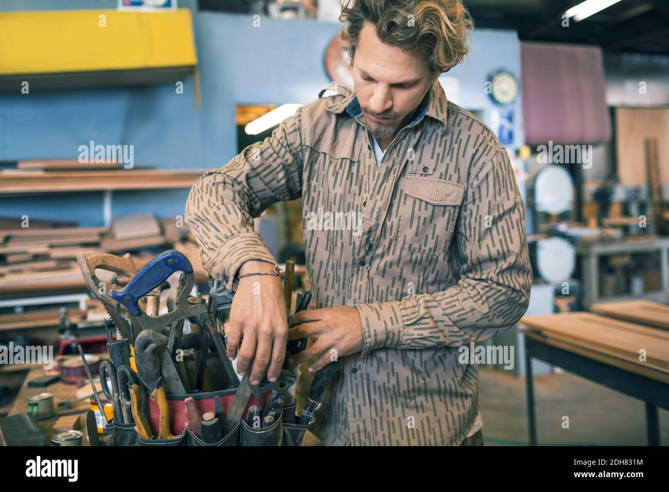 Carpenter arranging tools in belt at workshop Stock Photo - Alamy