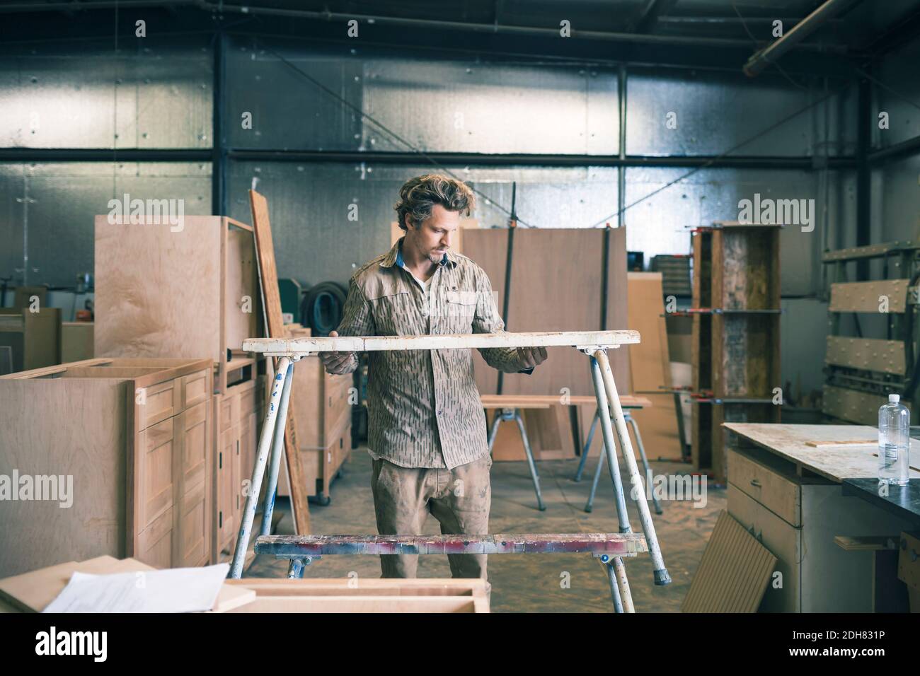 Carpenter holding table while working at workshop Stock Photo - Alamy