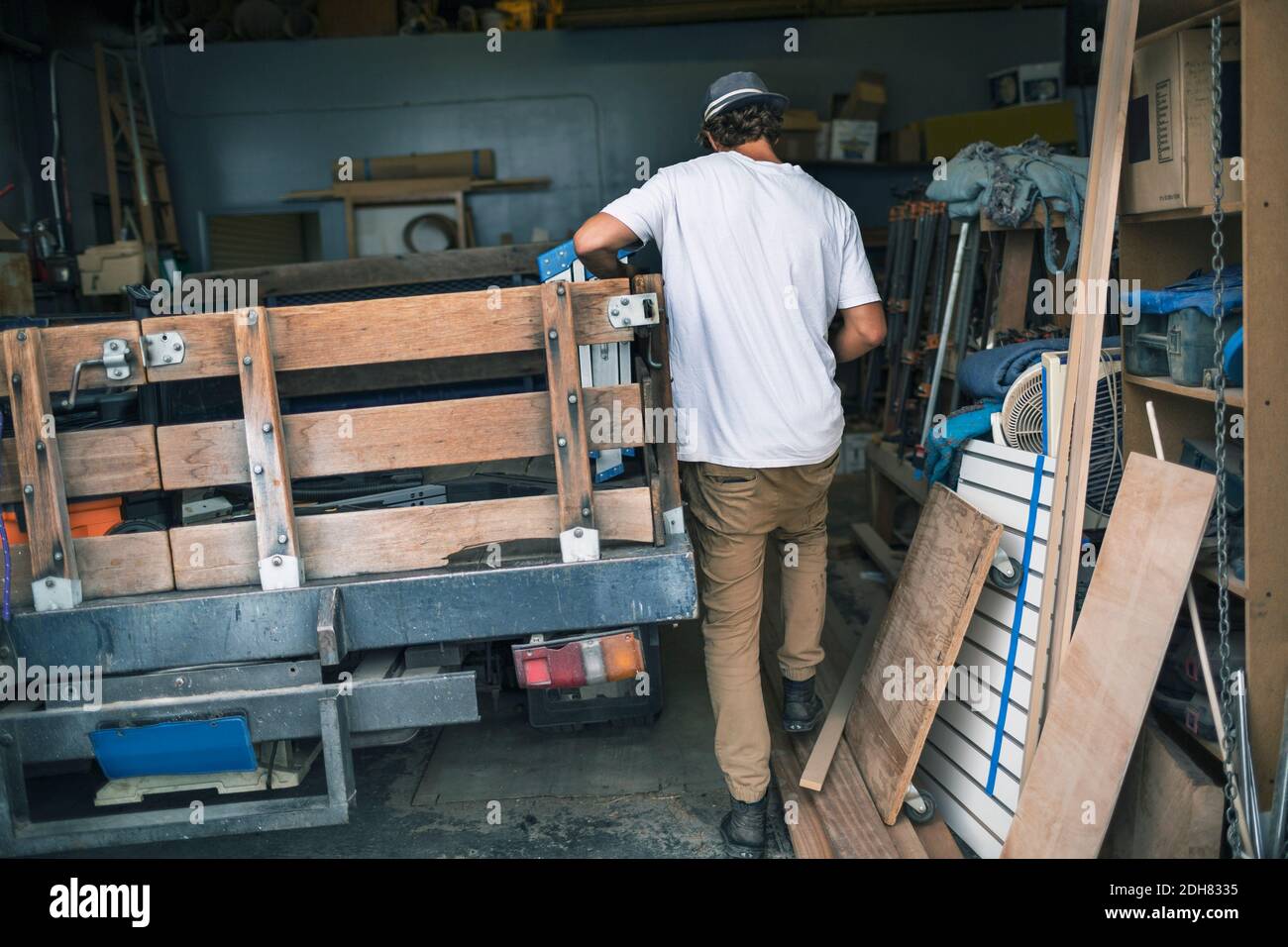 Rear view of carpenter walking by pick-up truck at workshop Stock Photo ...