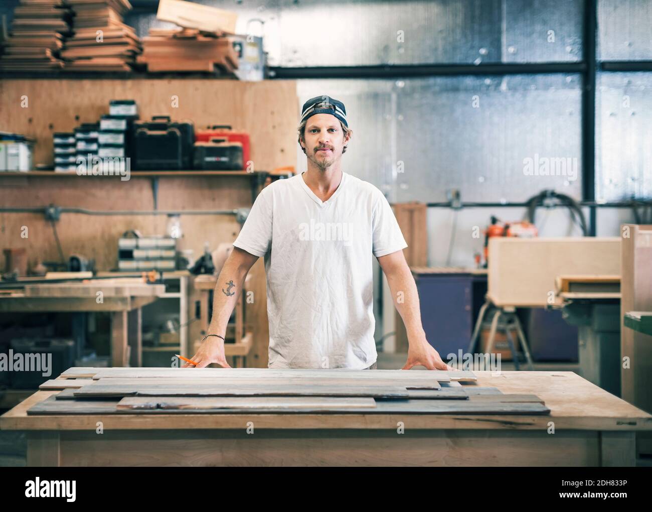 Portrait of confident carpenter standing at workbench in workshop Stock ...