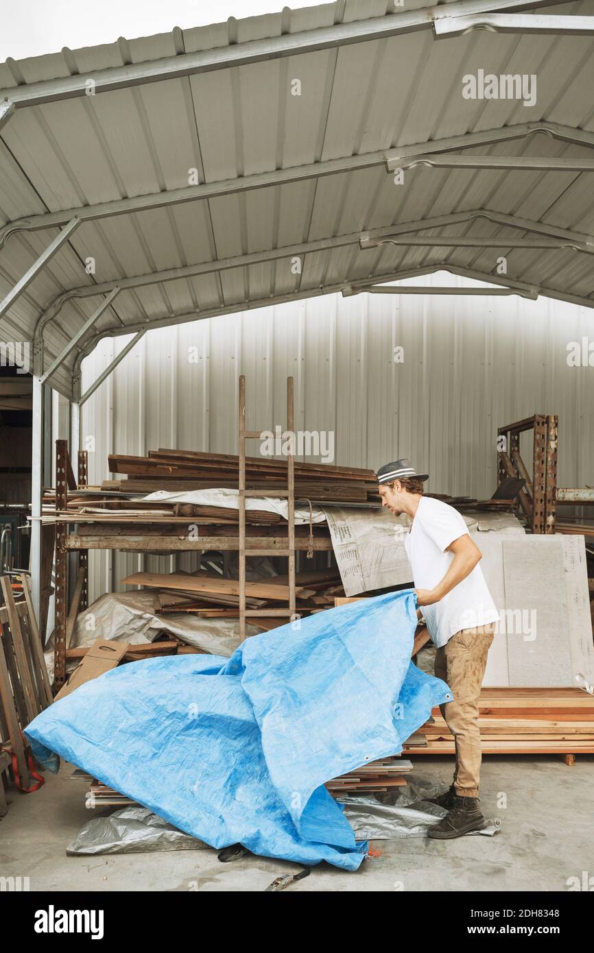 Side view of carpenter packing wood with plastic at workshop Stock ...