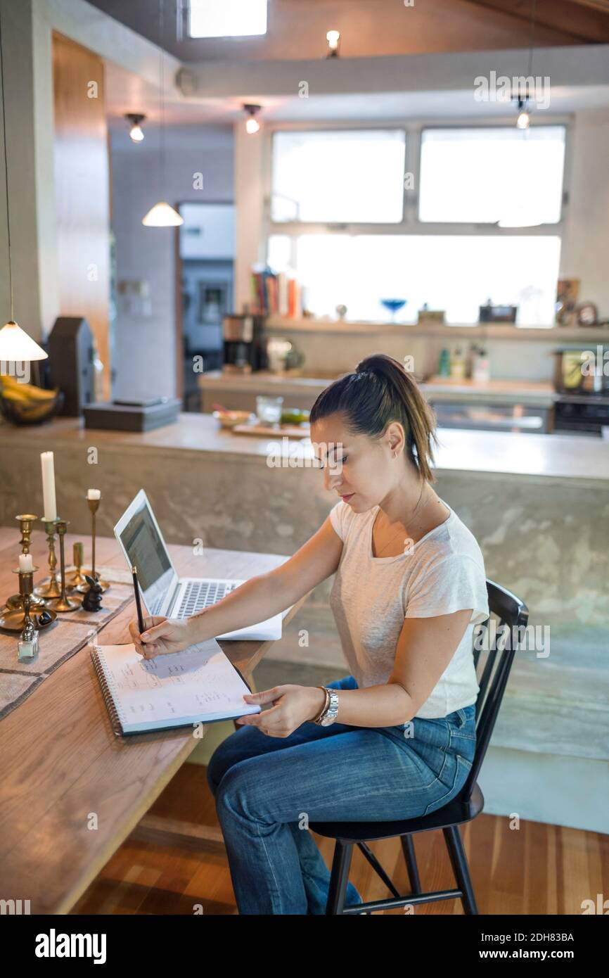 Woman working on laptop at dining table Stock Photo - Alamy