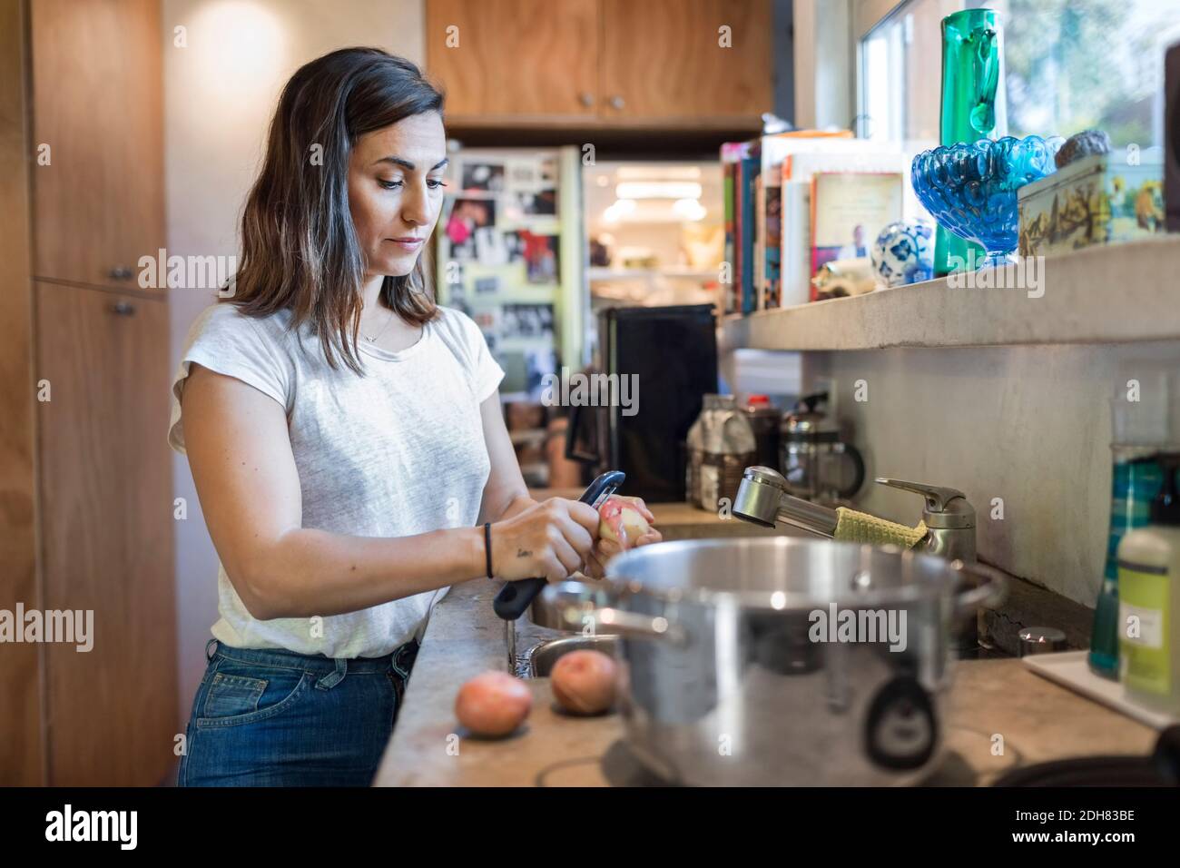 Woman peeling potato at kitchen counter Stock Photo - Alamy