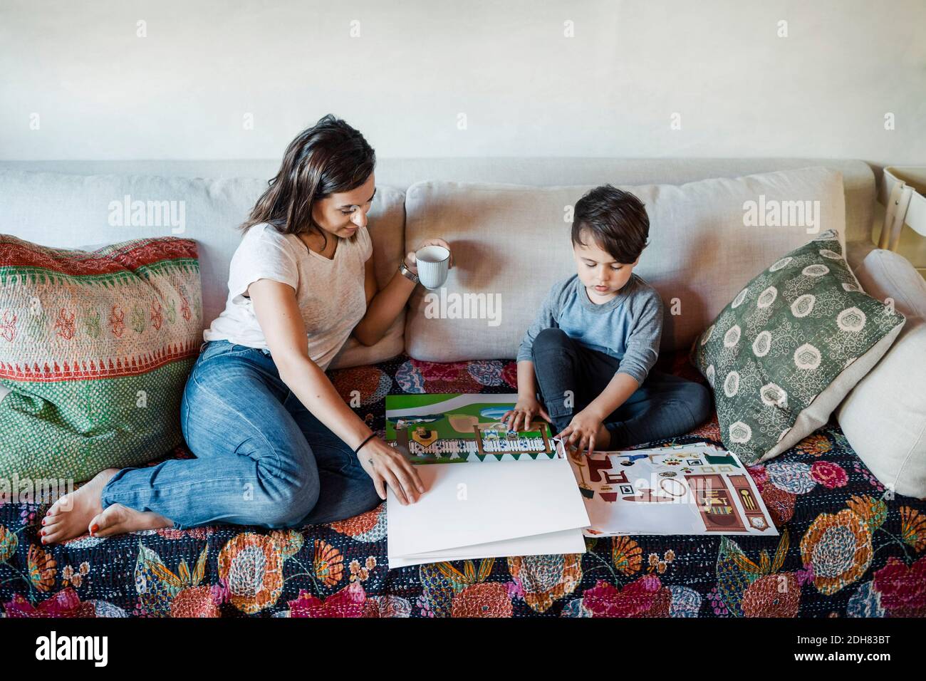 Mother assisting son in doing homework on sofa Stock Photo - Alamy