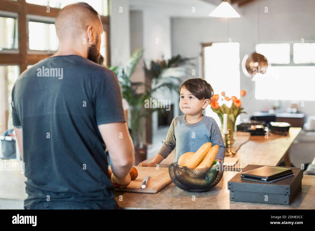 Boy looking at father standing at kitchen counter Stock Photo - Alamy