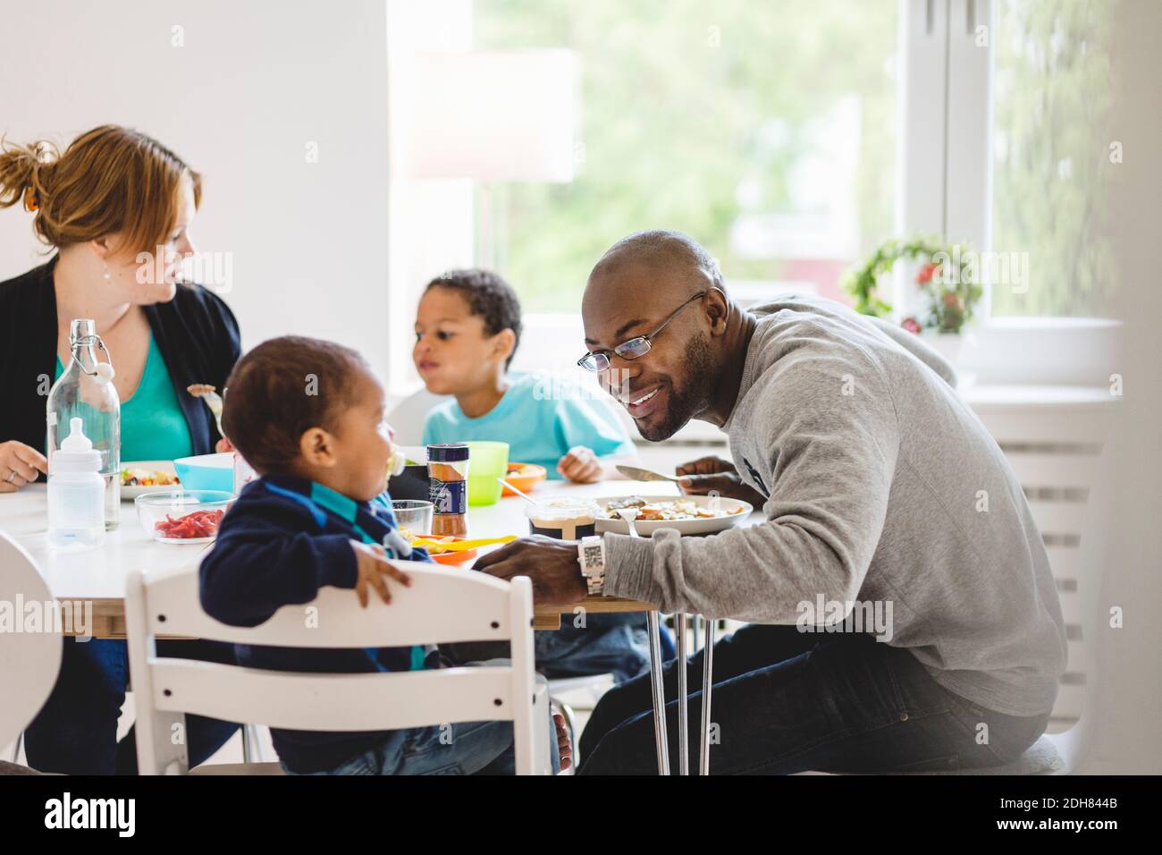 Multi-ethnic family having food at table in house Stock Photo - Alamy