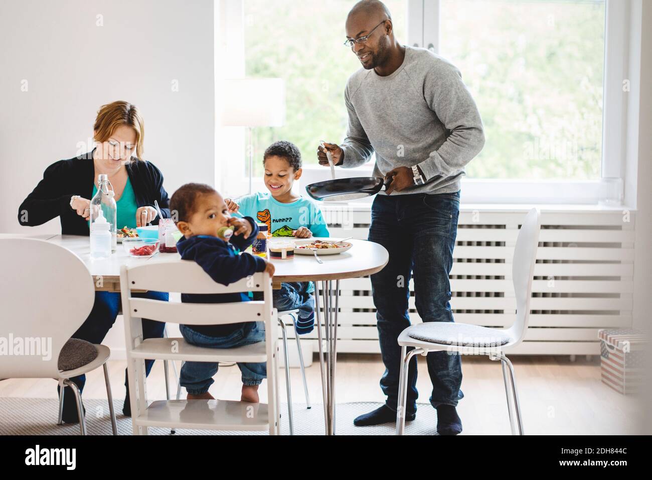 Man serving food to family at dining table in house Stock Photo - Alamy