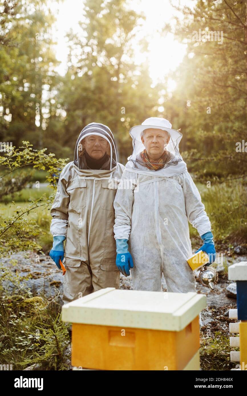 Portrait of confident beekeepers standing on field Stock Photo - Alamy
