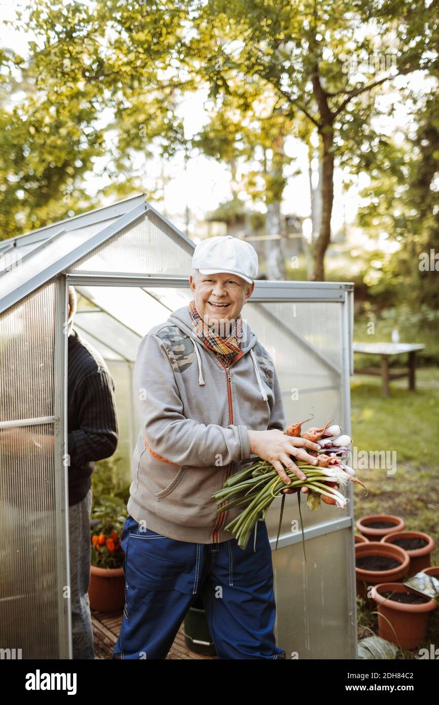 Happy gay man holding root vegetables at garden Stock Photo - Alamy