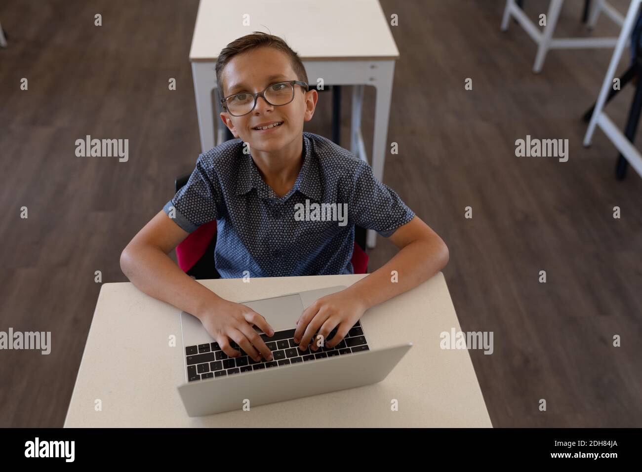 Schoolboy sitting at a desk using a laptop computer in an elementary ...