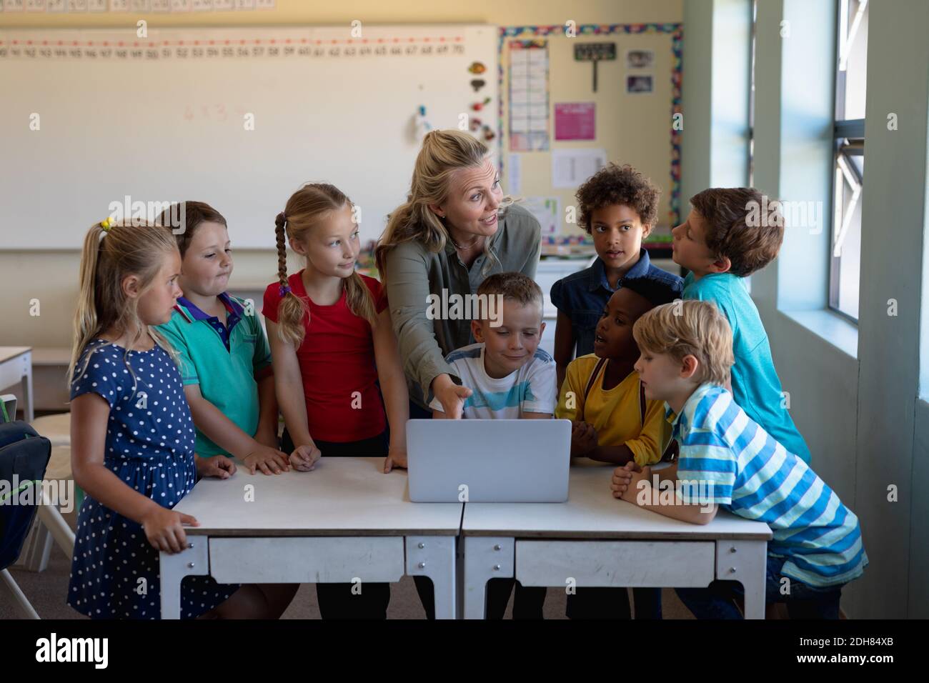 Female teacher using a laptop computer with of schoolchildren Stock ...