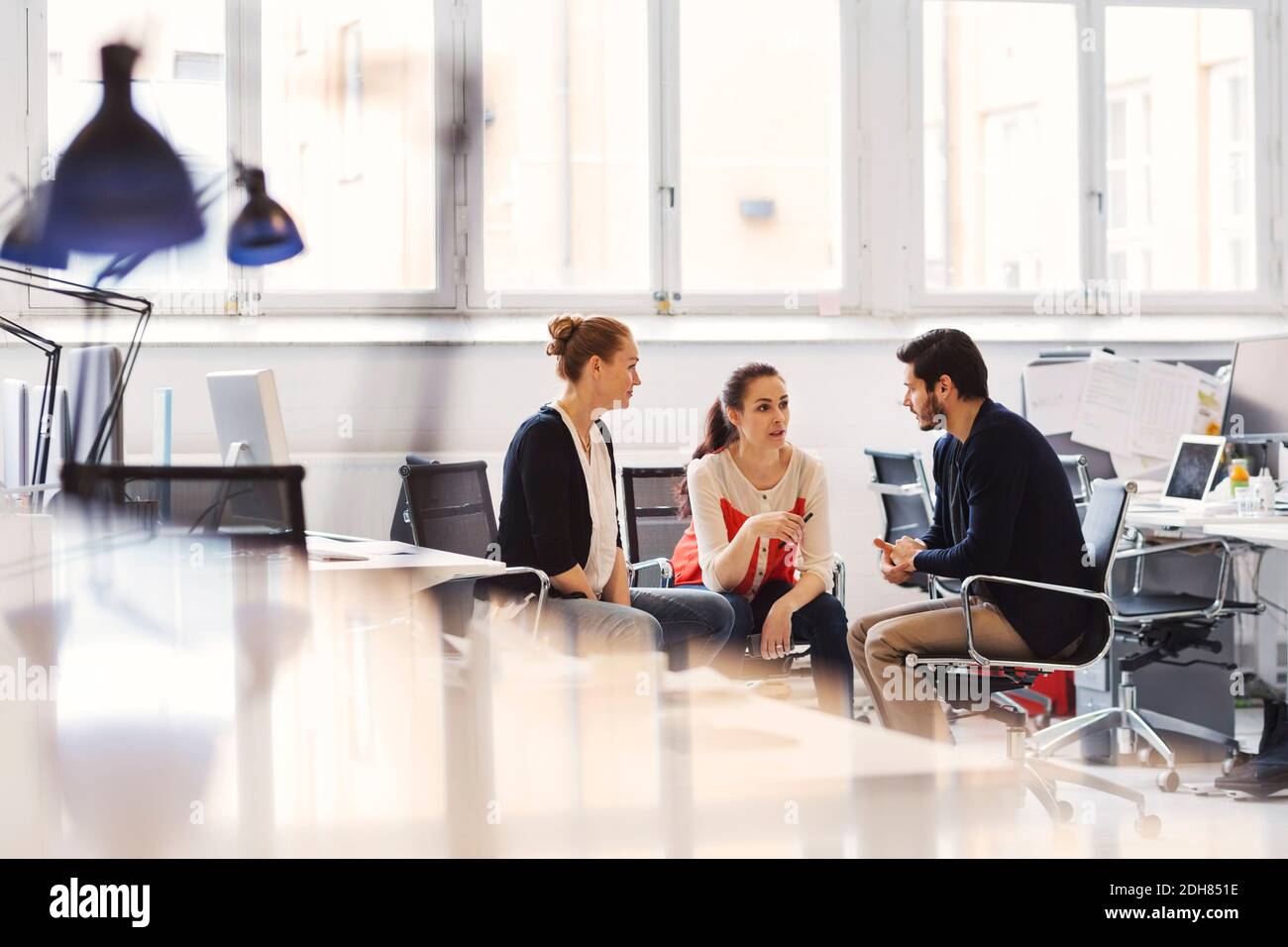 Mid adult businesswoman with colleagues having discussion in office ...