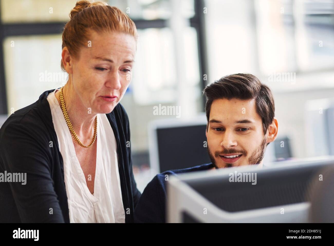 Businesswoman with male colleague using computer in office Stock Photo ...