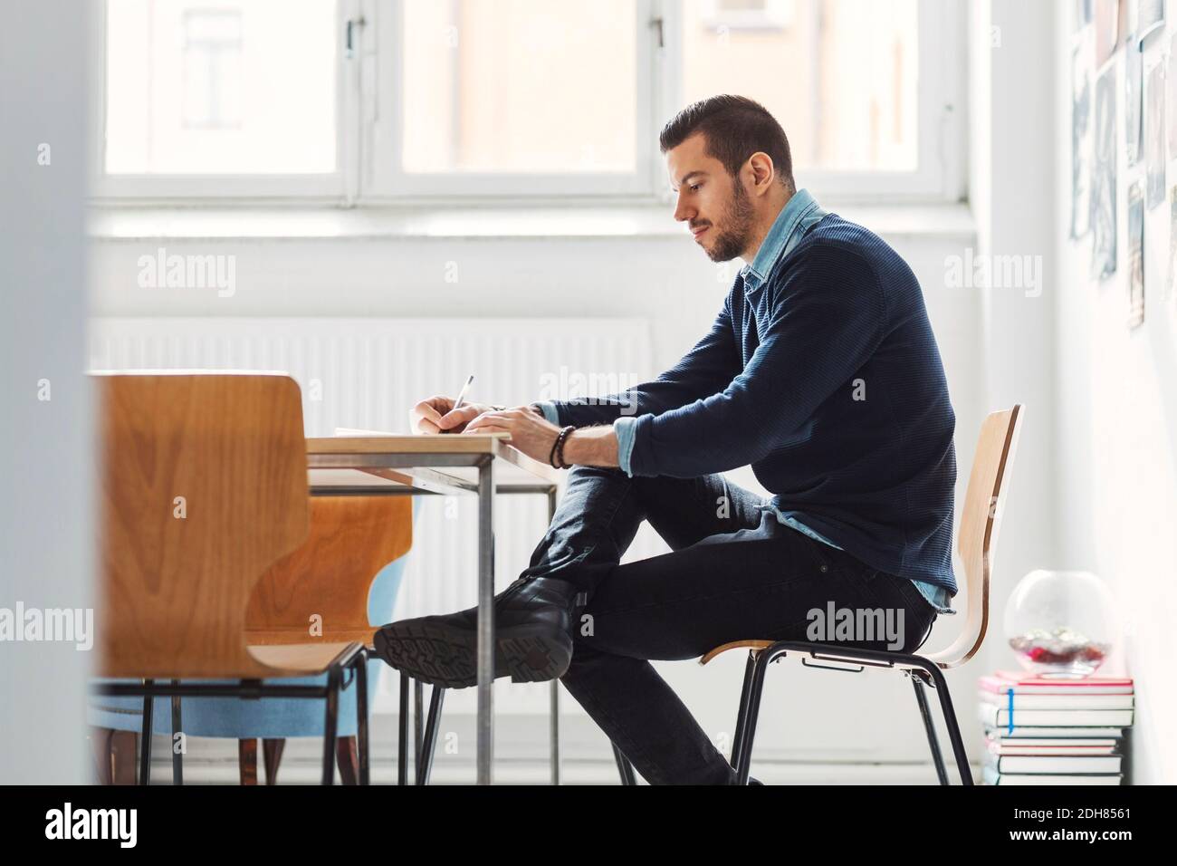 Side view of mid adult businessman writing in book at office desk Stock ...