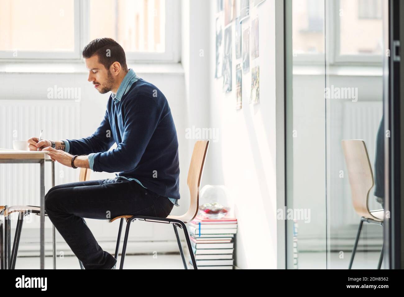 Side view of businessman writing in book at office desk Stock Photo - Alamy
