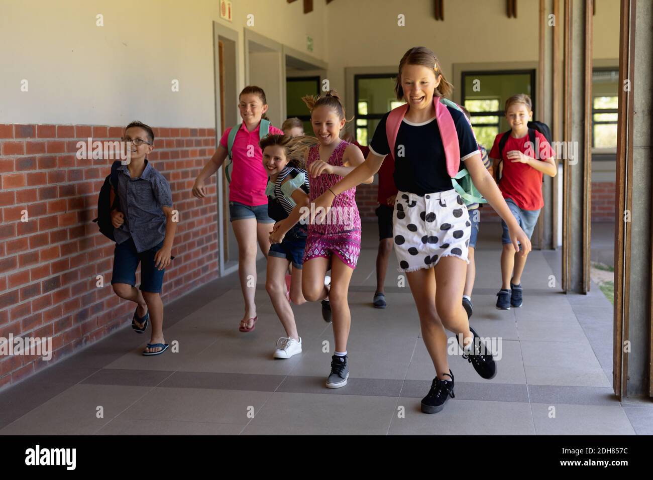 Group of schoolchildren running in an outdoor corridor at elementary ...