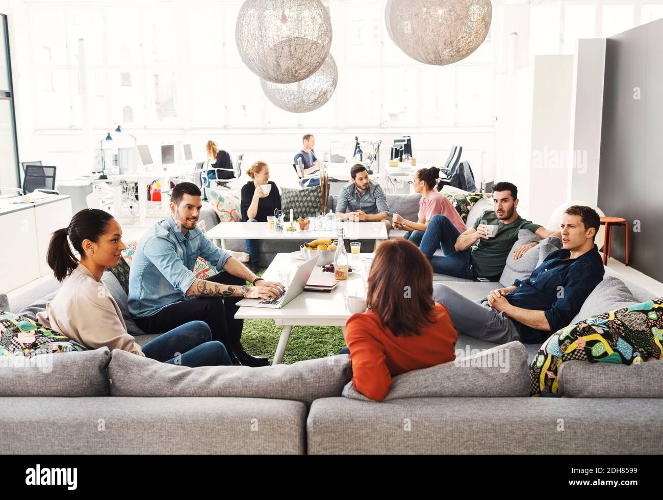 Multi-ethnic business people having discussion in modern office lobby ...