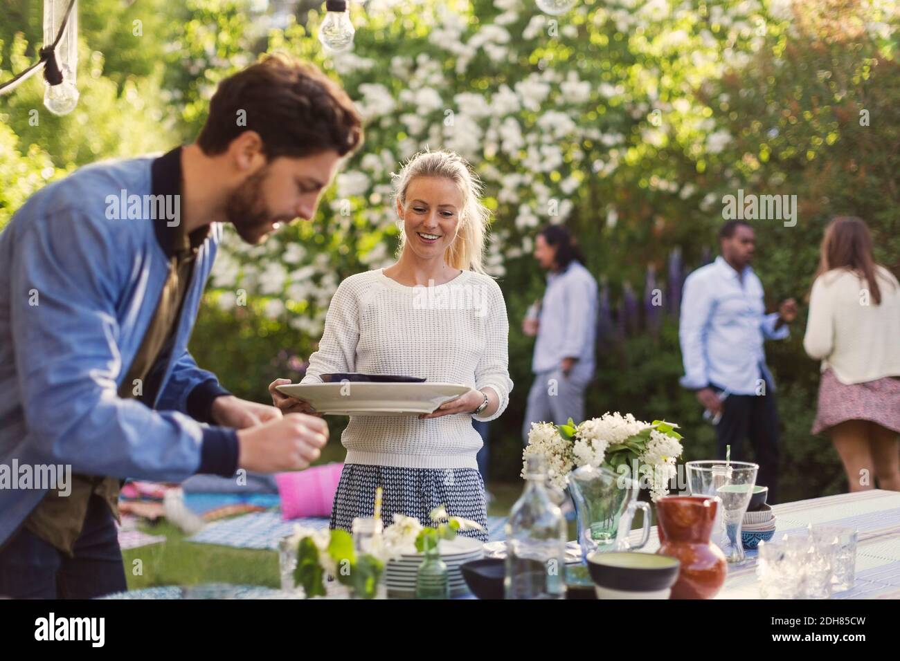 Happy young woman holding plates while enjoying summer party with ...