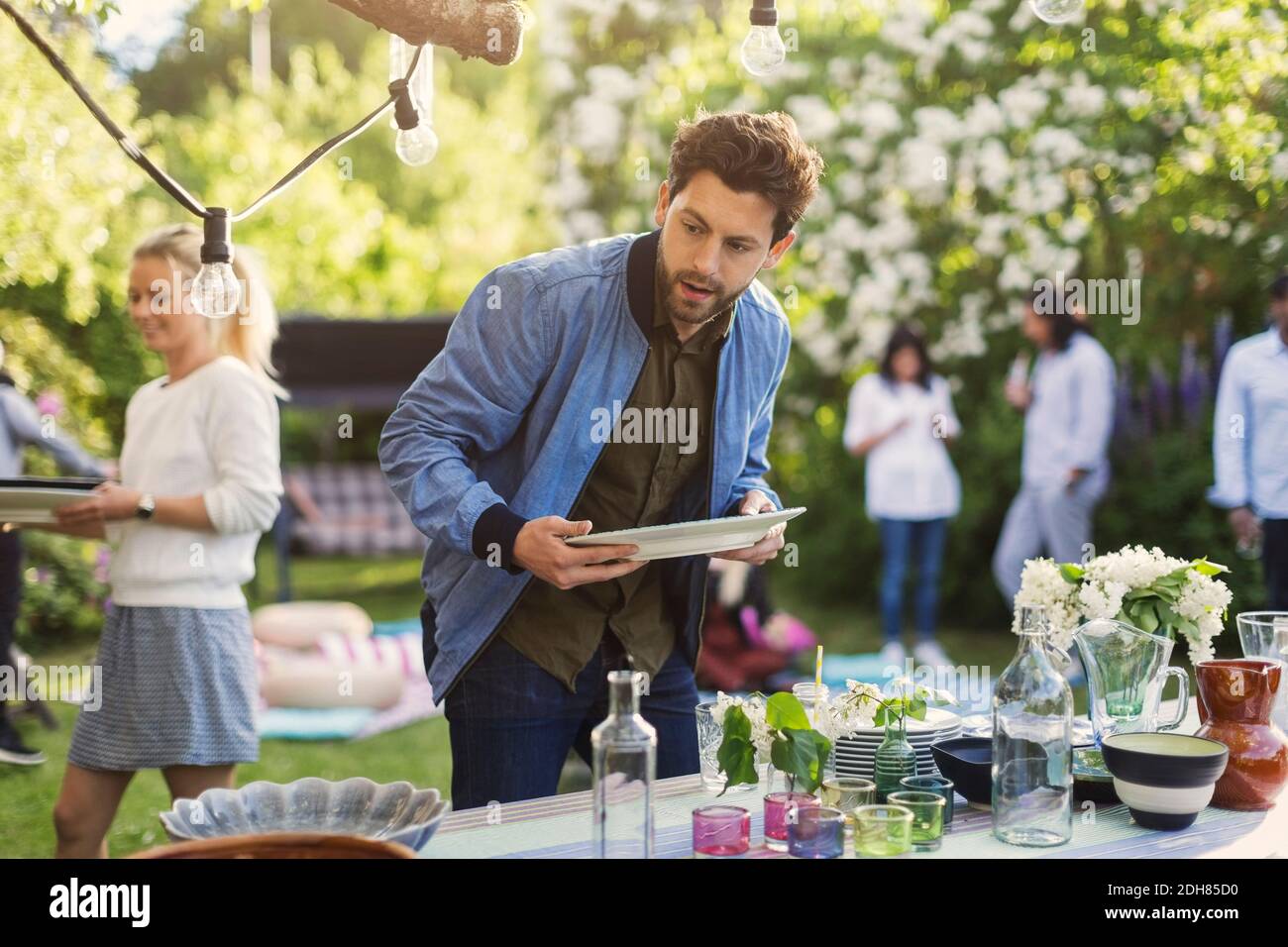 Young man holding empty plate at dining table in backyard during summer ...