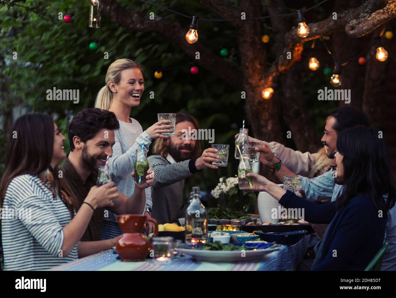 Multi-ethnic friends toasting drinks at dinner table in yard Stock ...