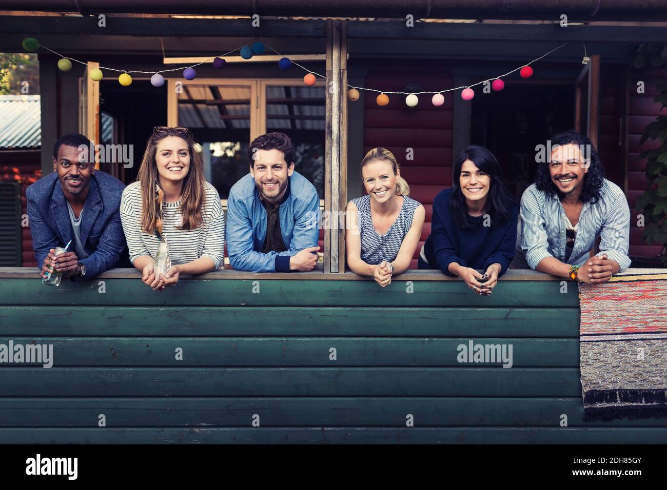 Portrait of multi-ethnic friends standing on porch at log cabin Stock ...
