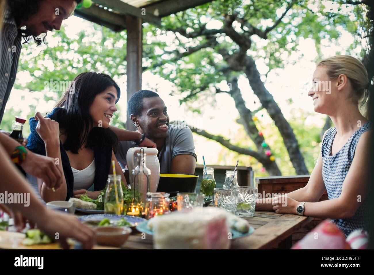 Happy multi-ethnic friends having food at porch in log cabin Stock ...