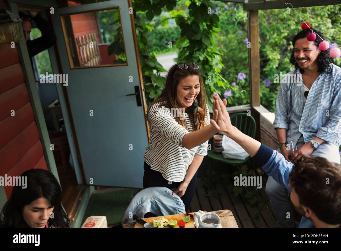 Happy friends giving high five while enjoying party in log cabin Stock ...