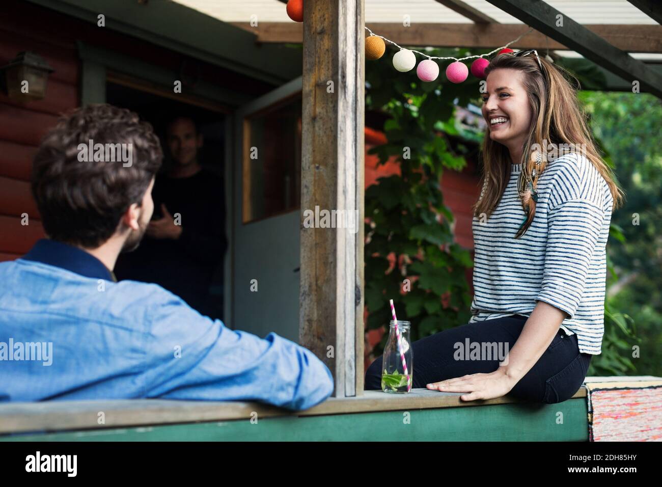 Happy woman sitting with friend at porch in log cabin Stock Photo - Alamy