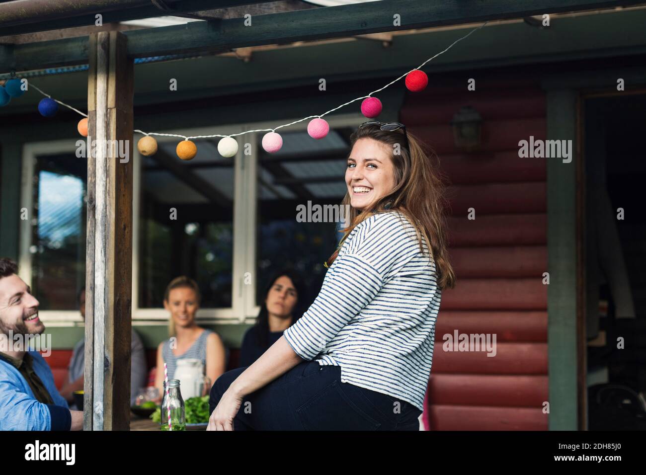 Side view portrait of happy woman sitting with friends in log cabin ...