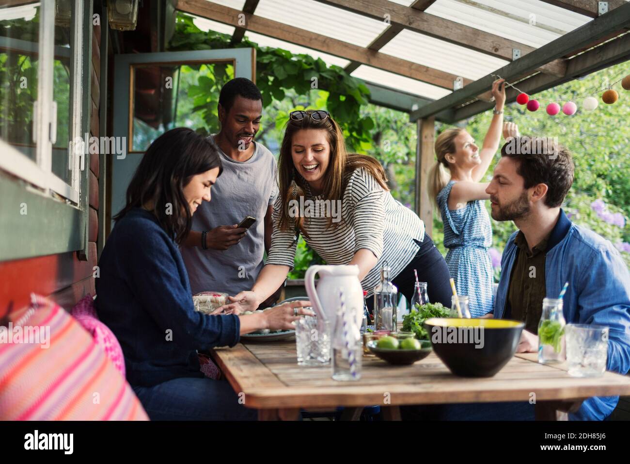 Happy friends enjoying party at porch in summer house Stock Photo - Alamy
