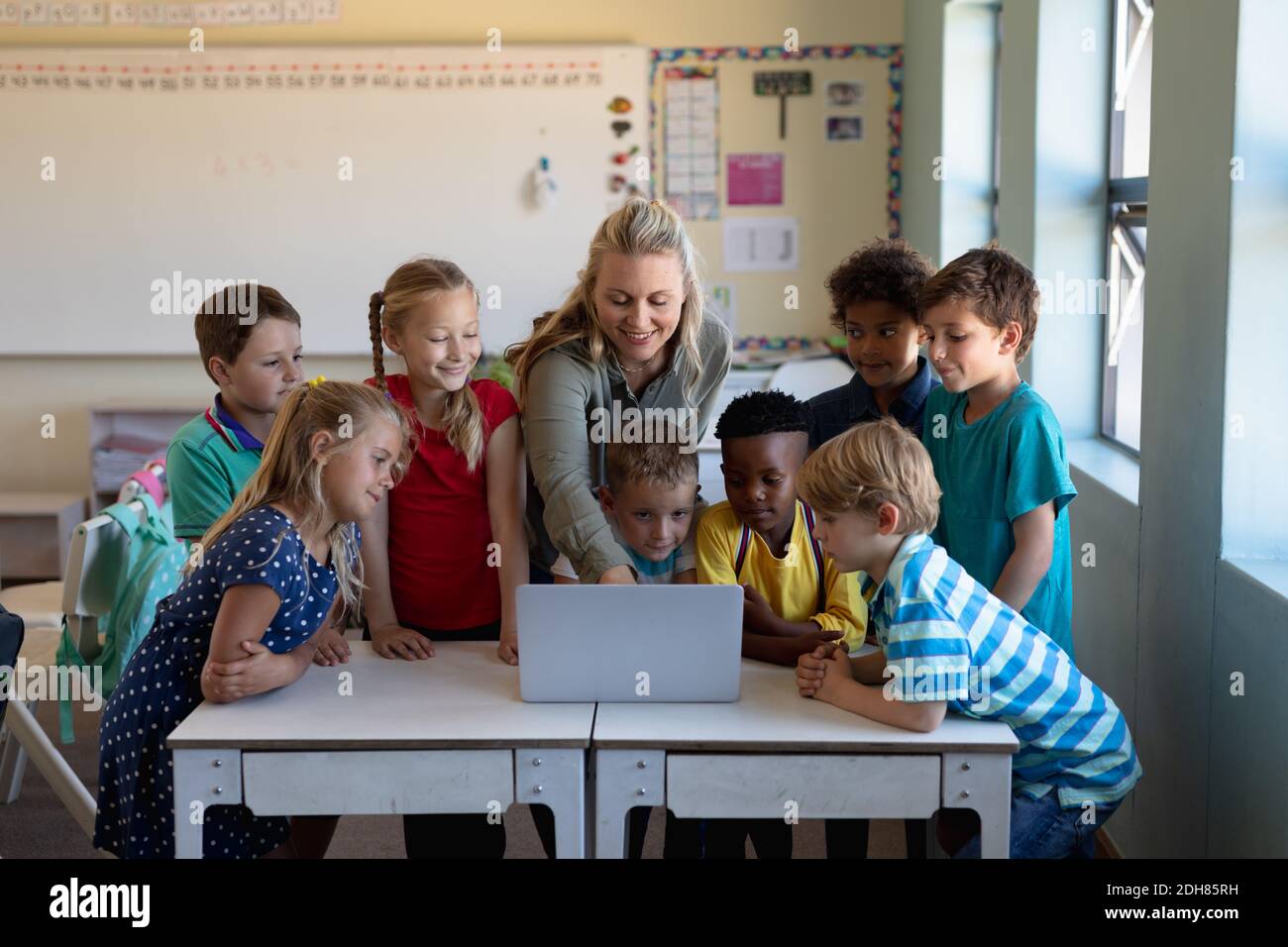 Female teacher using a laptop computer with group of schoolchildren ...